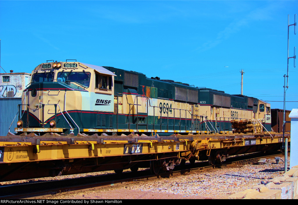 BNSF 9694 leads an empty coal past an empty pipe train.